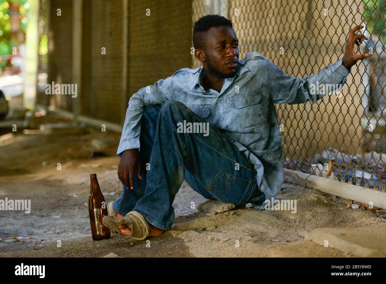 Young homeless African man with bottle of beer in the streets Stock ...