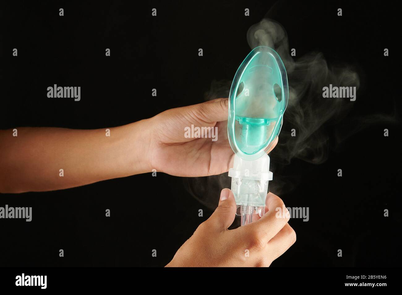 Close up of working inhaler mask with smoke isolated on black ...