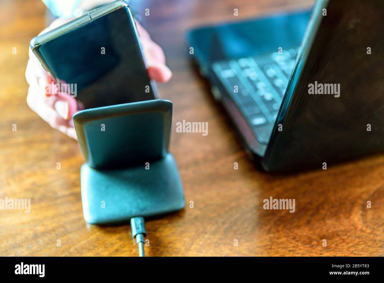 man charging smartphone using Wireless charging stand at home office ...