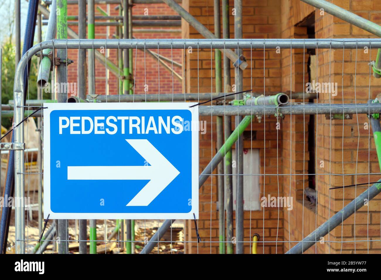 pedestrians directions lsign on fence over construction site in england ...