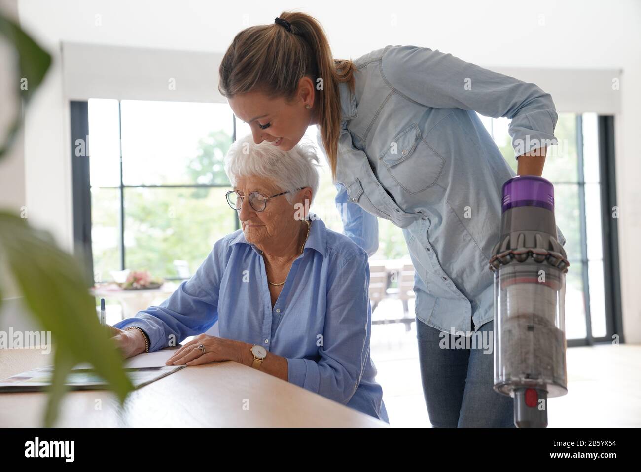 Elderly woman at home with homehelp doing household chores Stock Photo ...