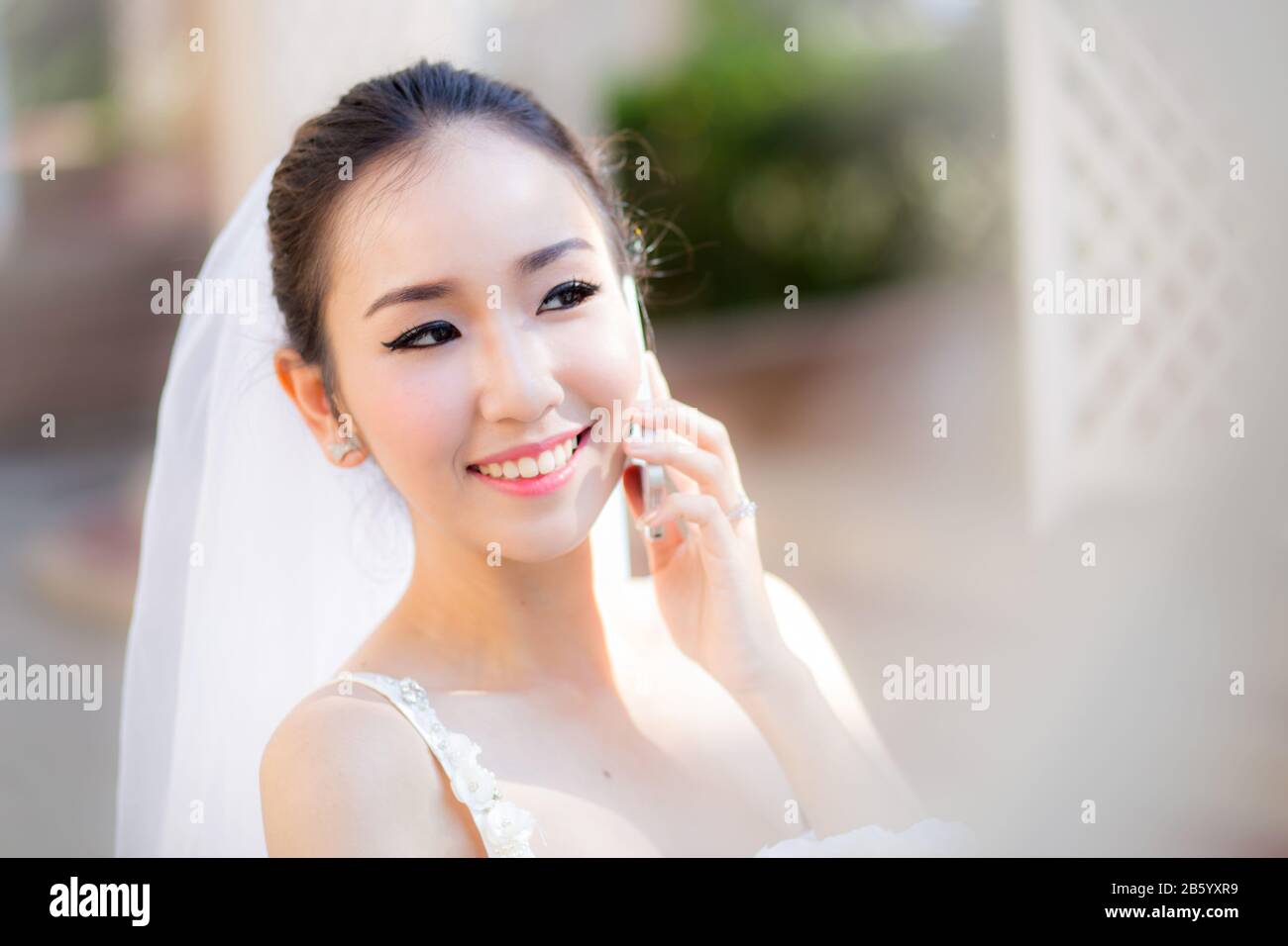 Happy bride talking on cell phone in wedding dress Stock Photo - Alamy