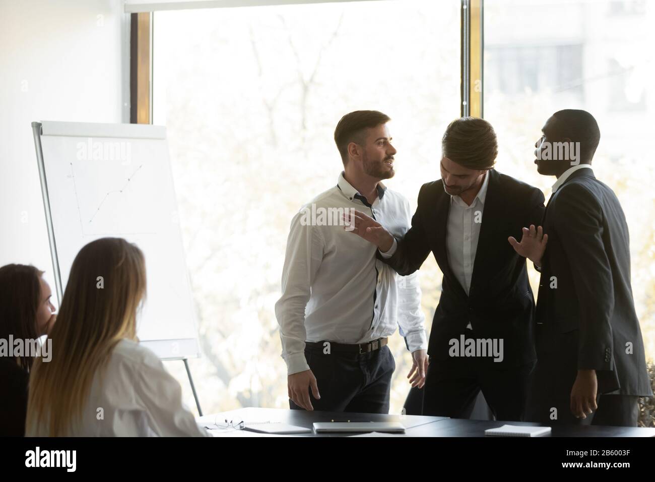 Millennial businessman setting apart two aggressive multiracial ...