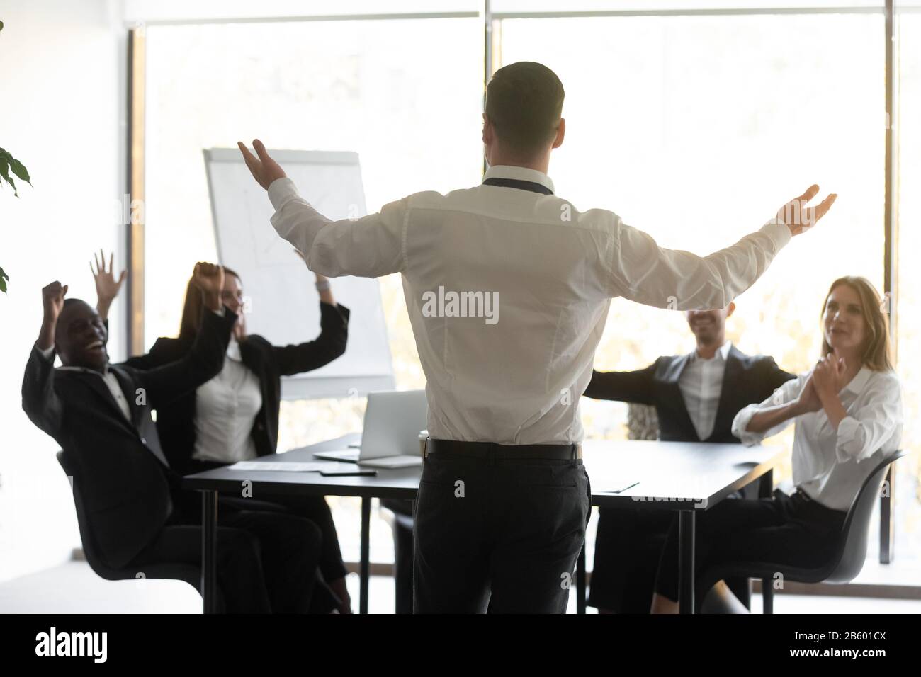 Rear view young team leader standing with raised hands Stock Photo - Alamy