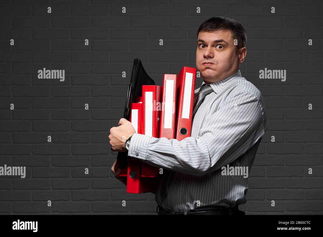 Very busy businessman closeup portrait, posing with red folders ...