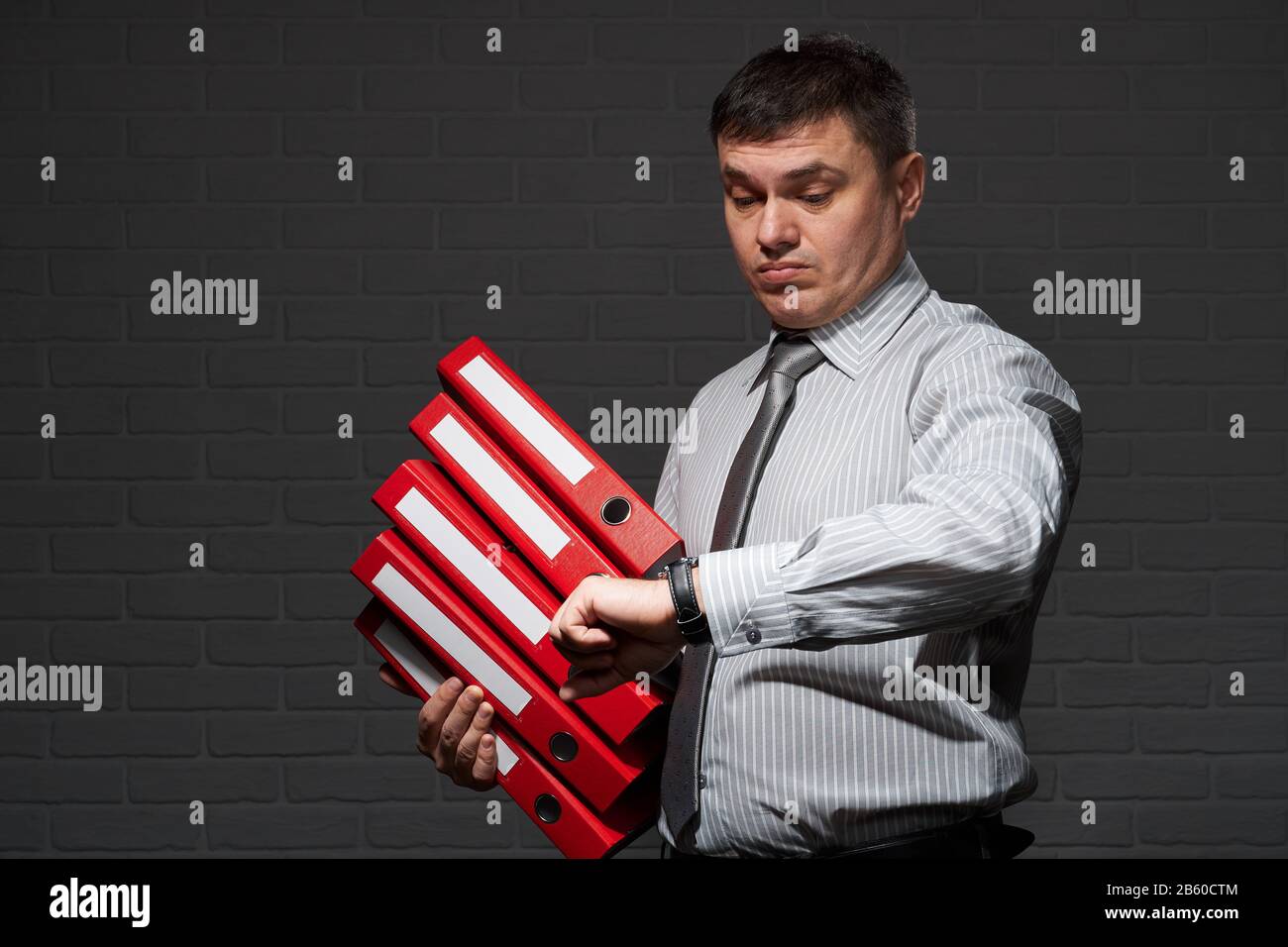 Very busy businessman closeup portrait, posing with red folders ...
