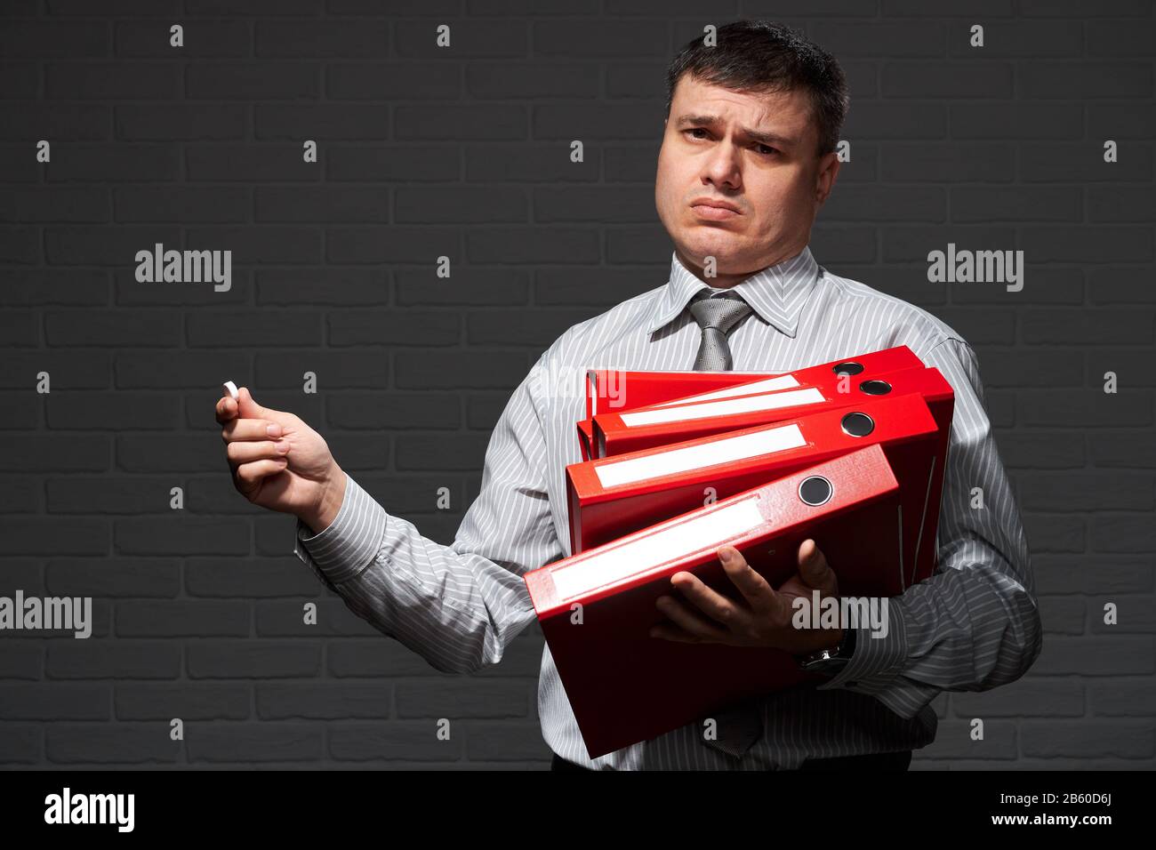 Very busy businessman closeup portrait, posing with red folders ...