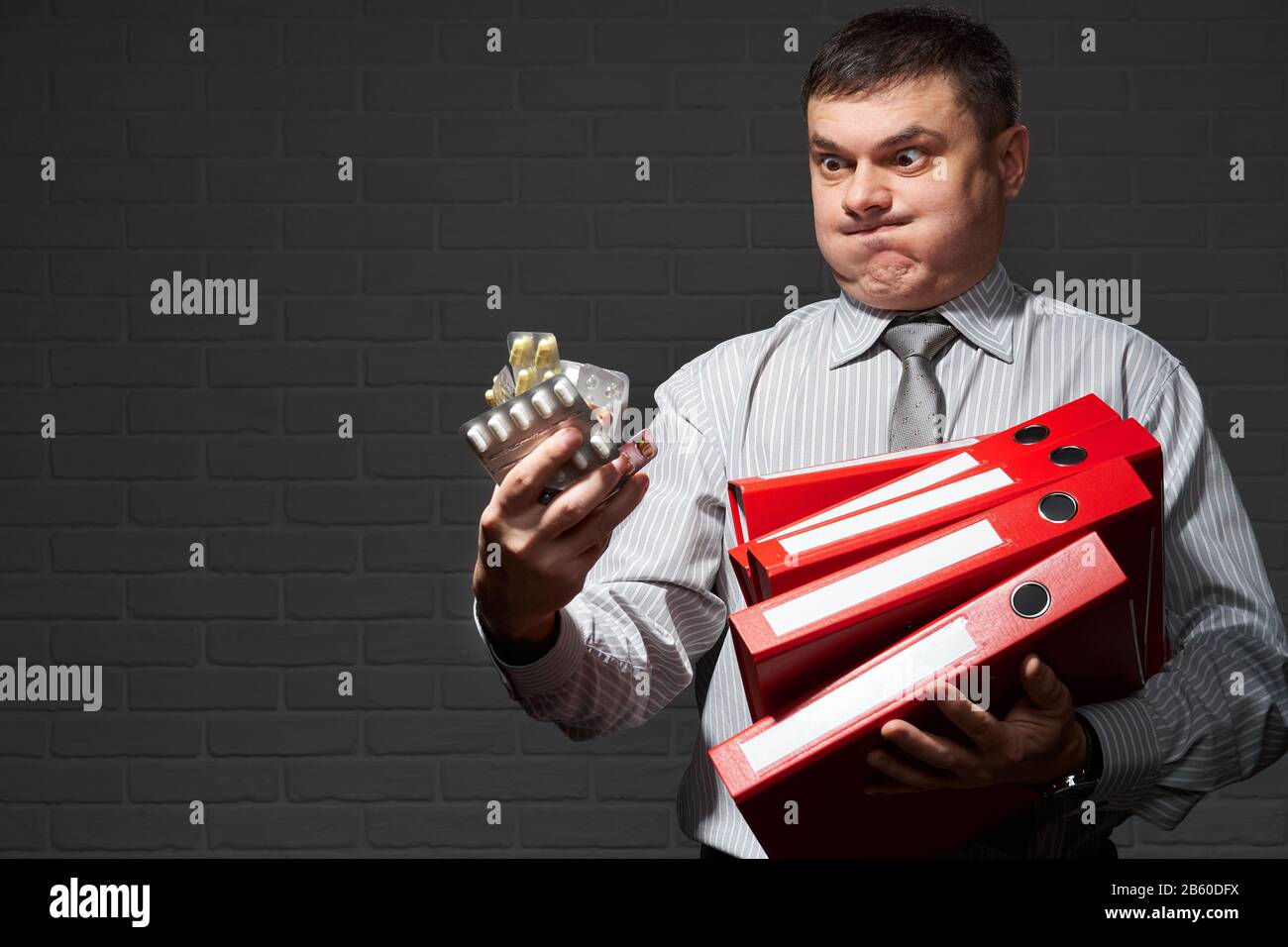 Very busy businessman closeup portrait, posing with red folders ...