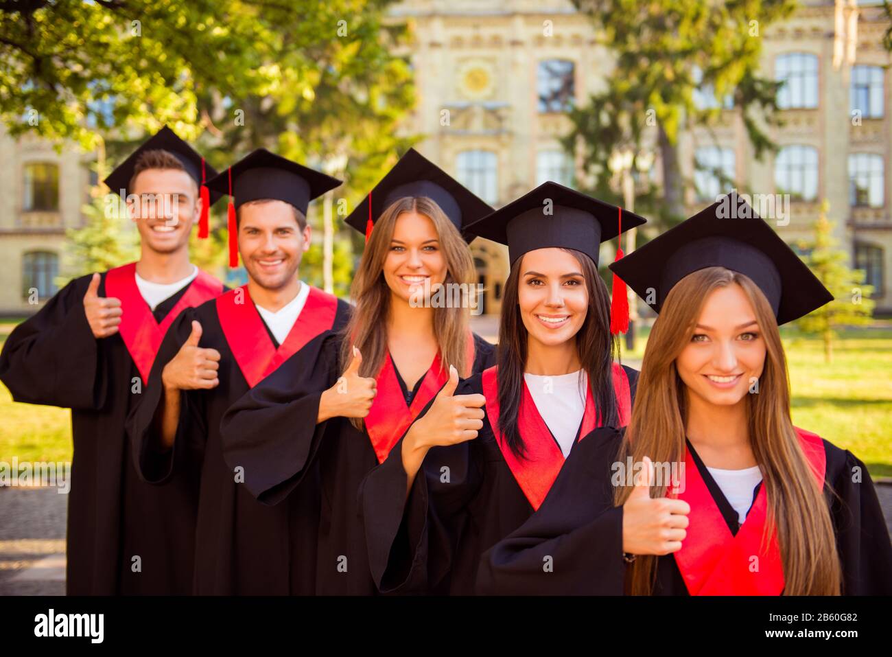 successful confident five graduates in robes and hats with tassel ...
