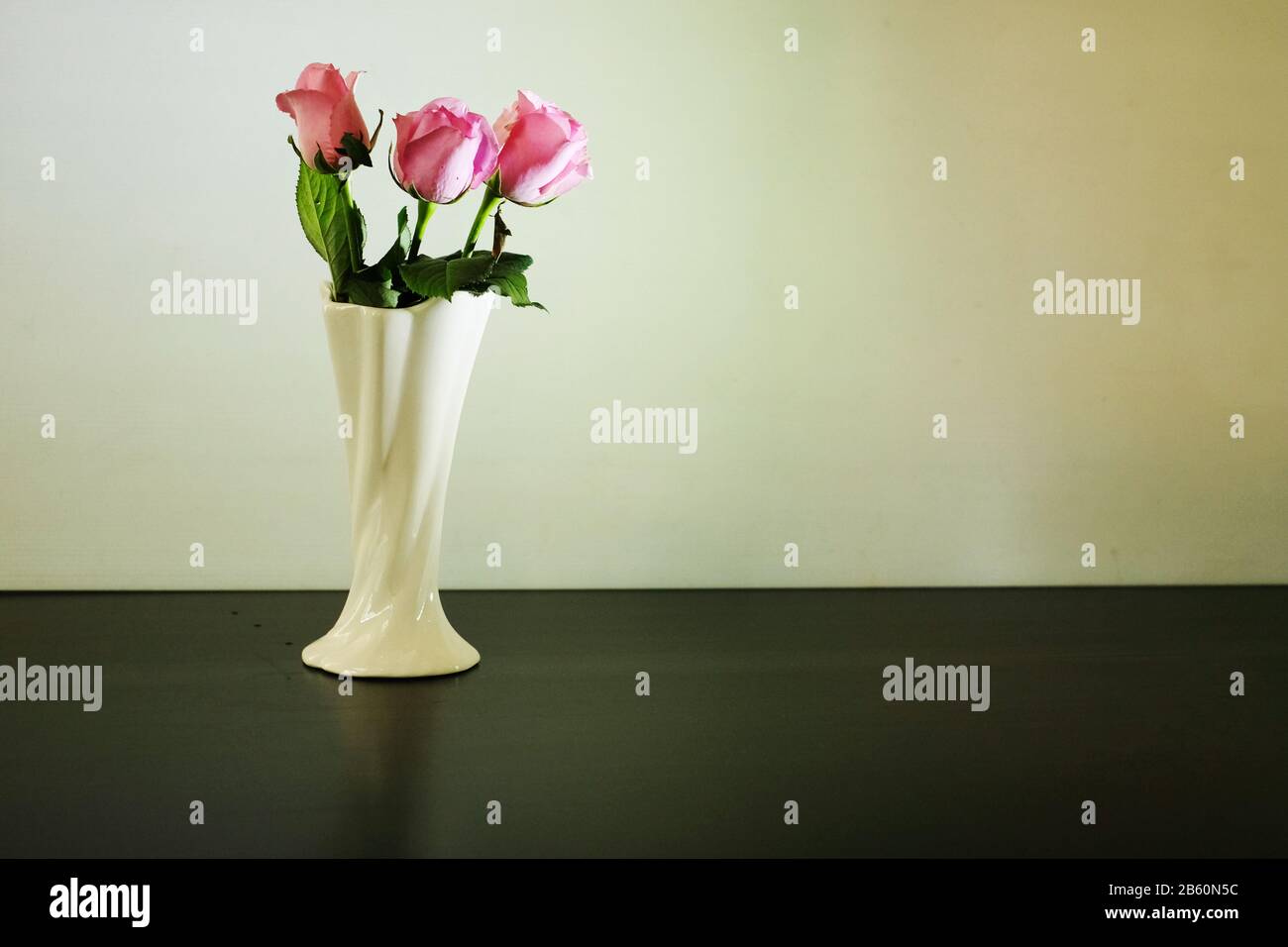 Three pink roses in vase on white background Stock Photo - Alamy
