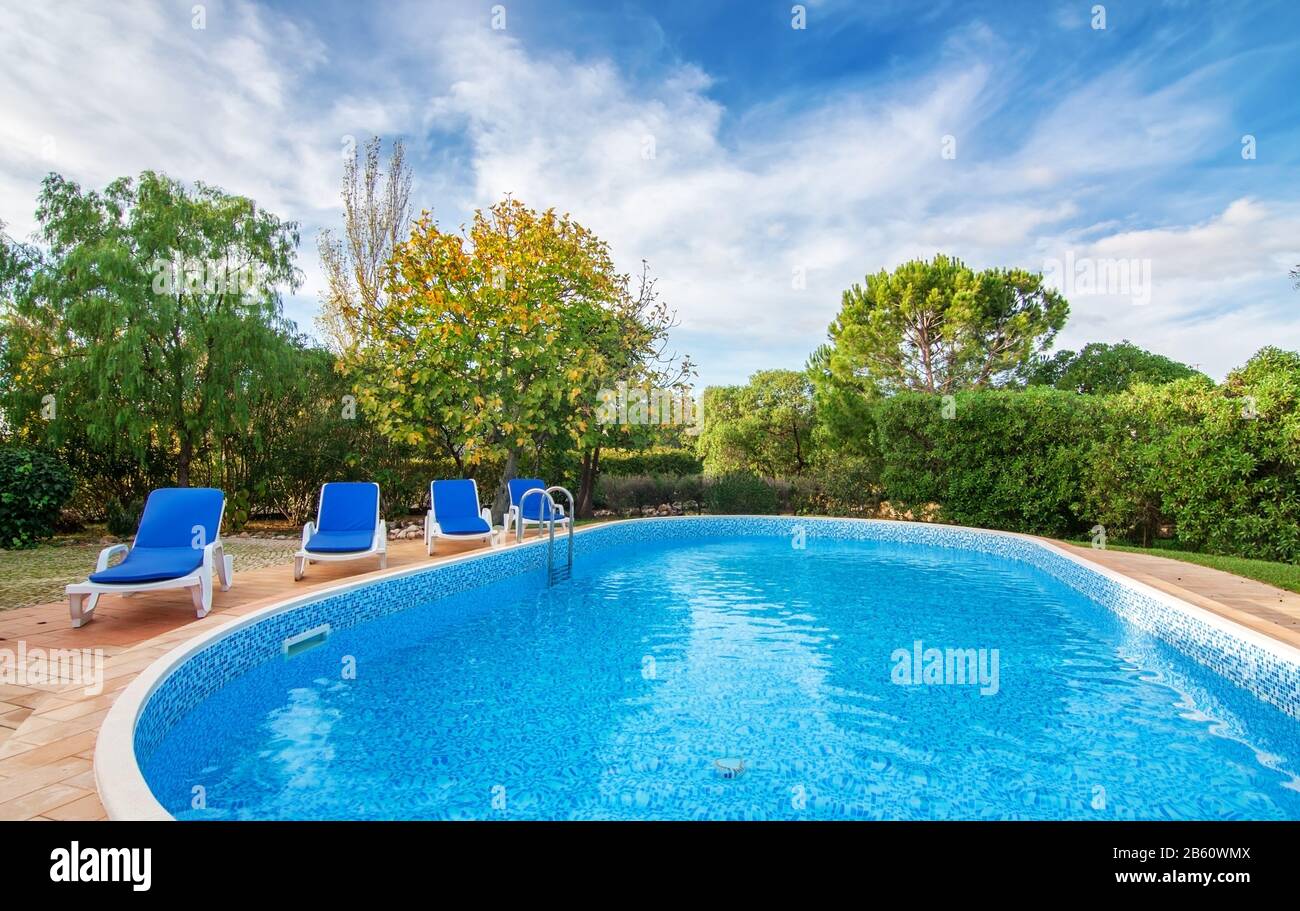 Swimming pool garden in summer with sun beds for relaxing. With clean ...
