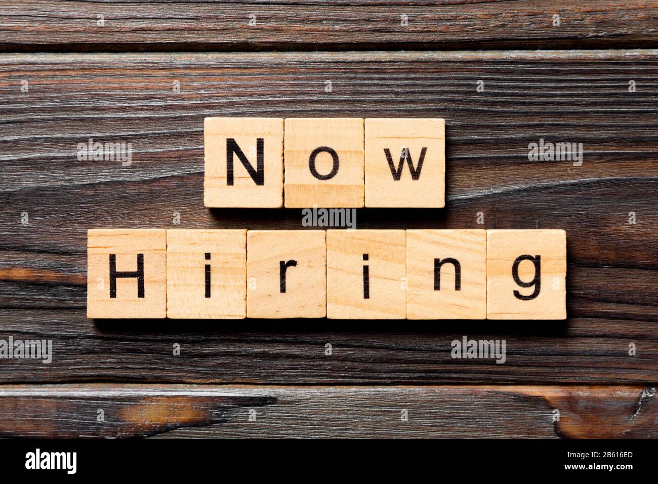 Now hiring word written on wood block. Now hiring text on wooden table ...