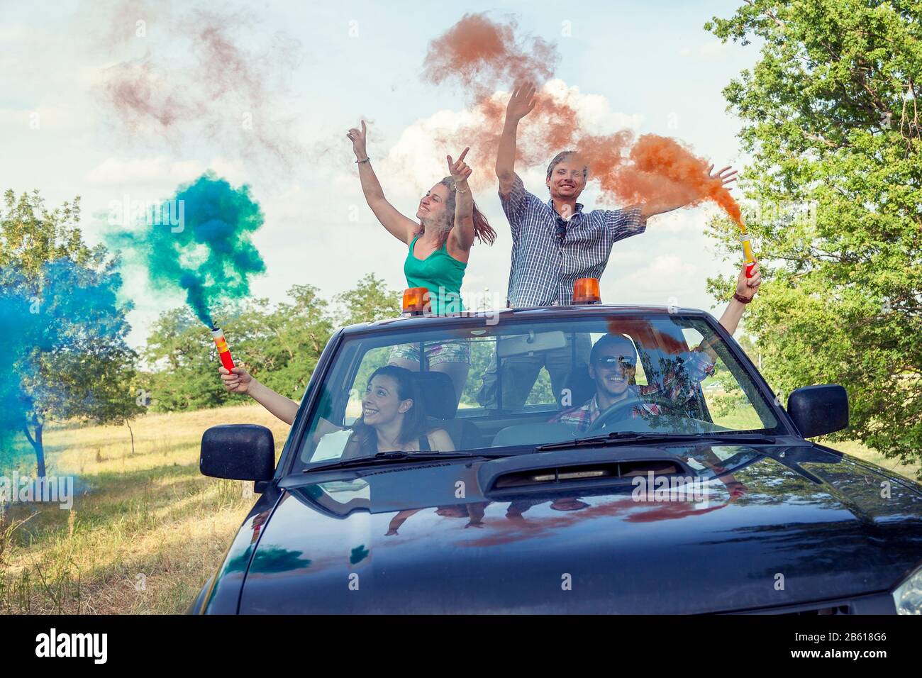 Group of young guys have fun with colored smoke trails driving in the ...