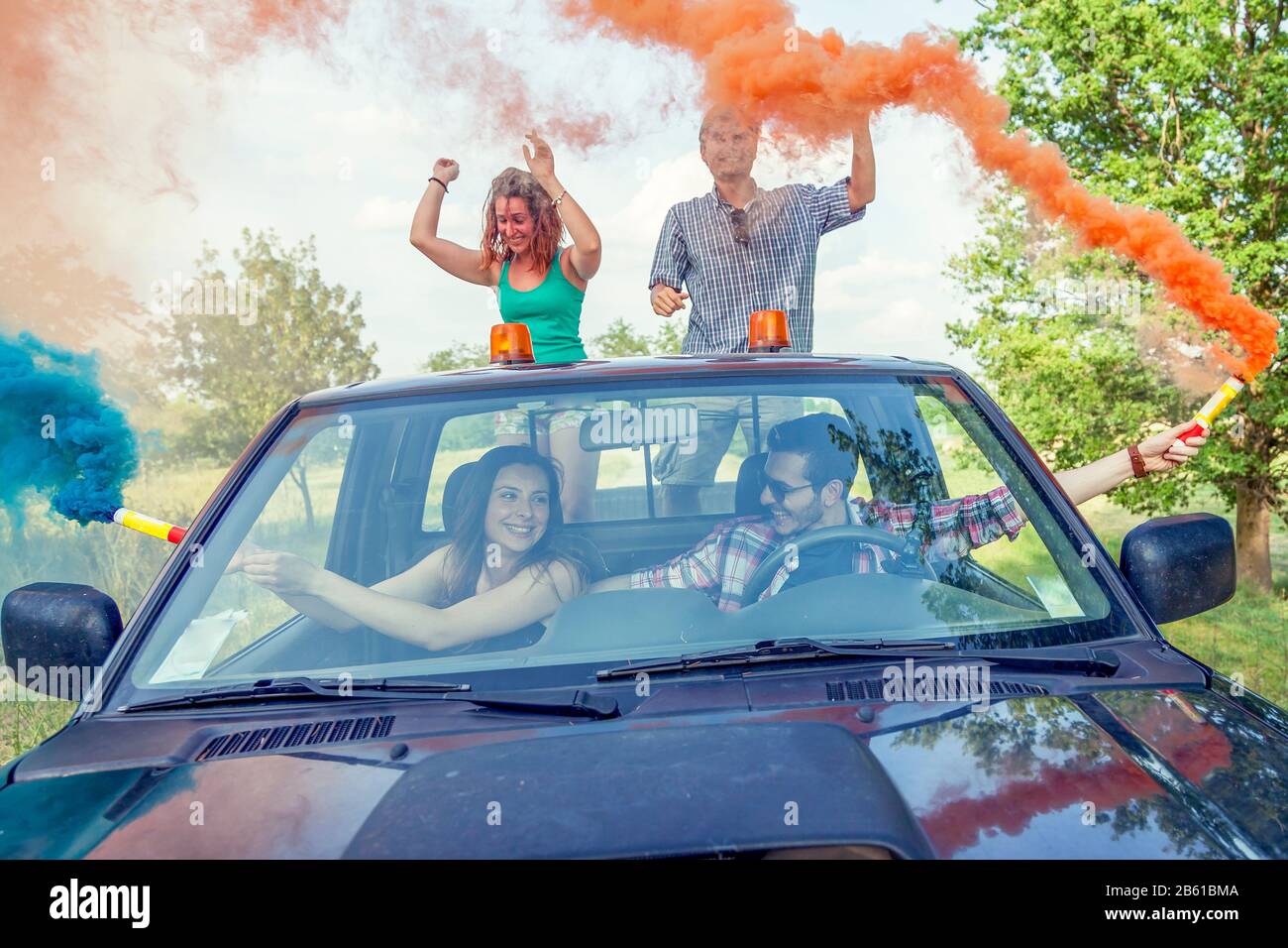 Group of young guys have fun with colored smoke trails driving in the ...