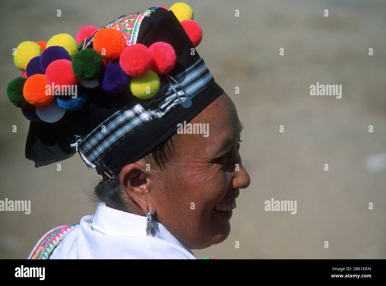 Lao woman in traditional dress, including a multi-coloured pom-pom hat ...