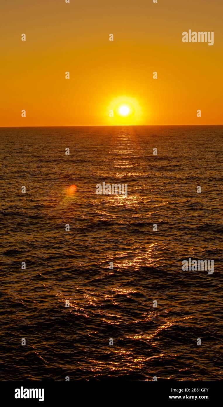 sunset in the middle of the ocean, the sun sets on the horizon with the ...