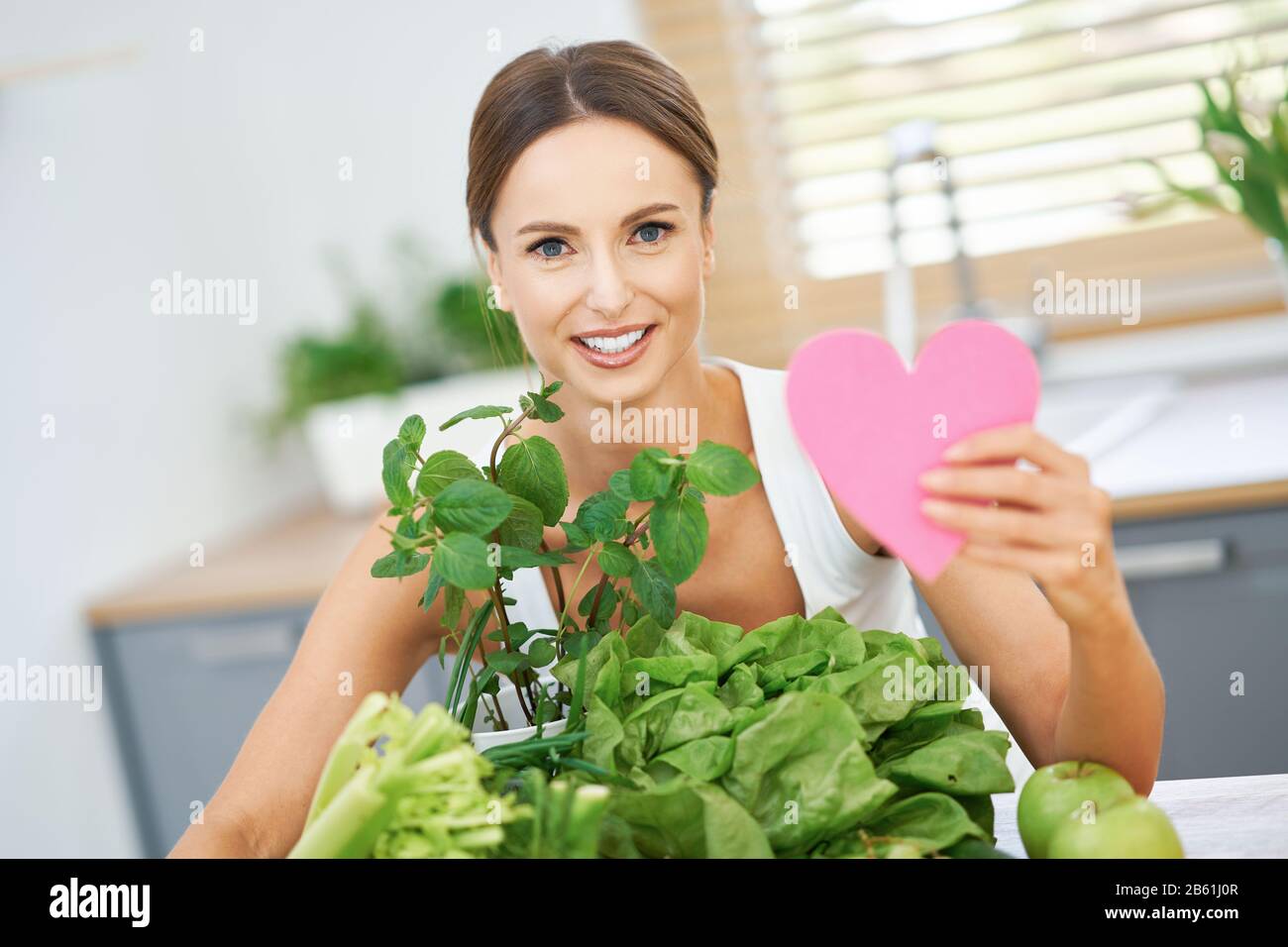 Healthy adult woman with green food in the kitchen Stock Photo - Alamy