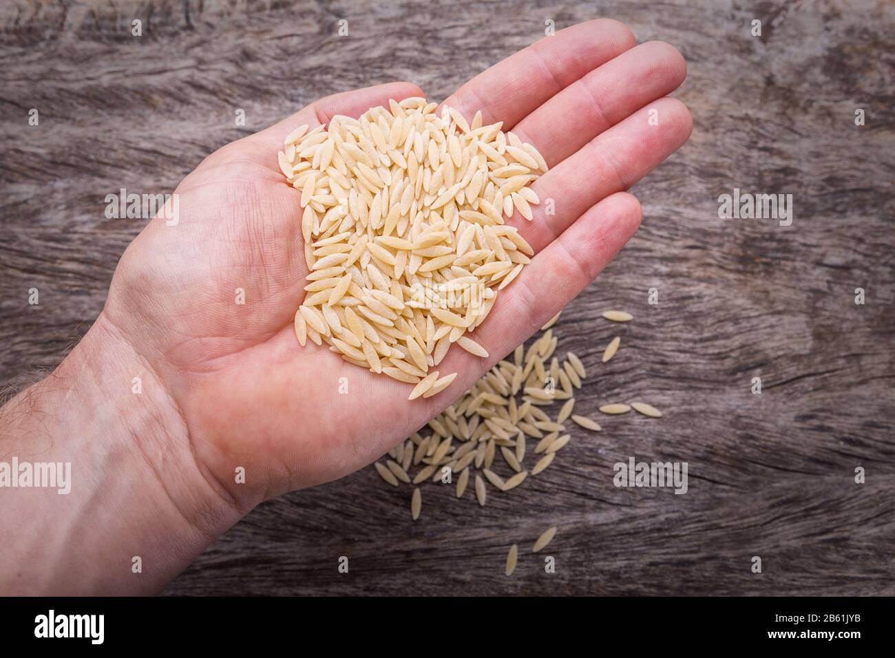 Raw rice in a man's hand. On a background of a wooden texture Stock ...