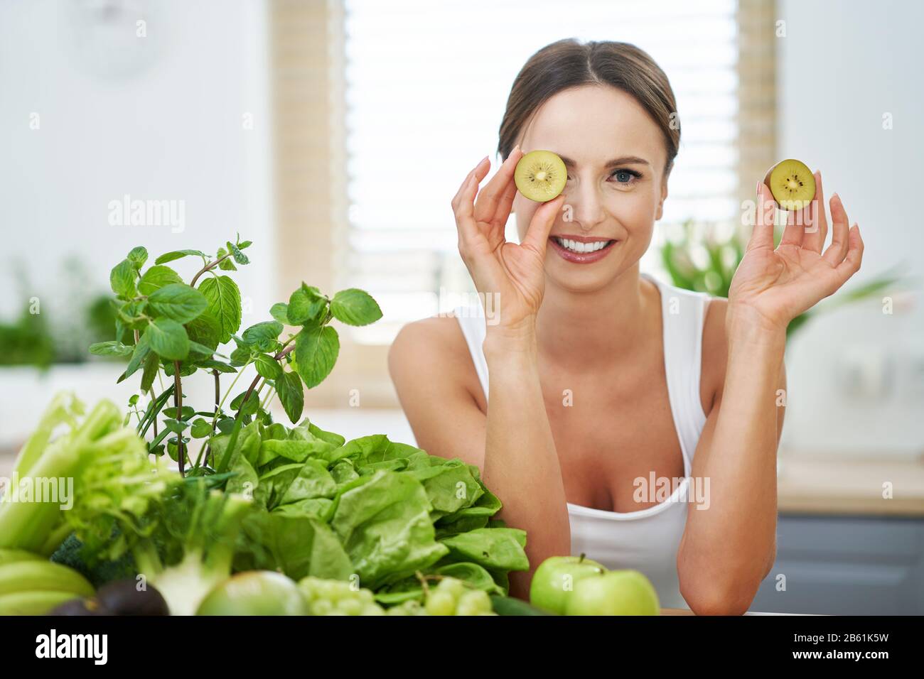 Healthy adult woman with green food in the kitchen Stock Photo - Alamy