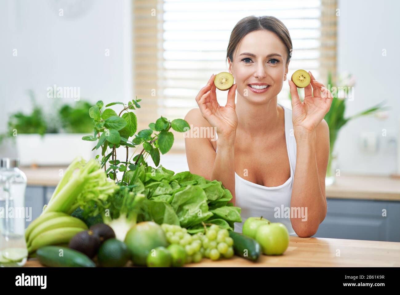 Healthy adult woman with green food in the kitchen Stock Photo - Alamy