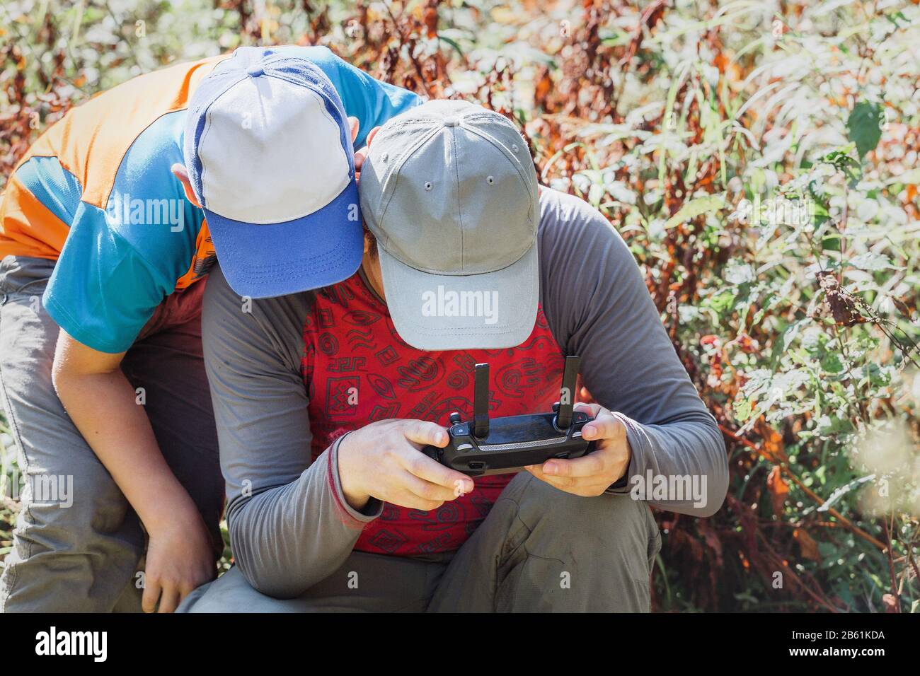 Father and son looking at remote control joystick and piloting ...