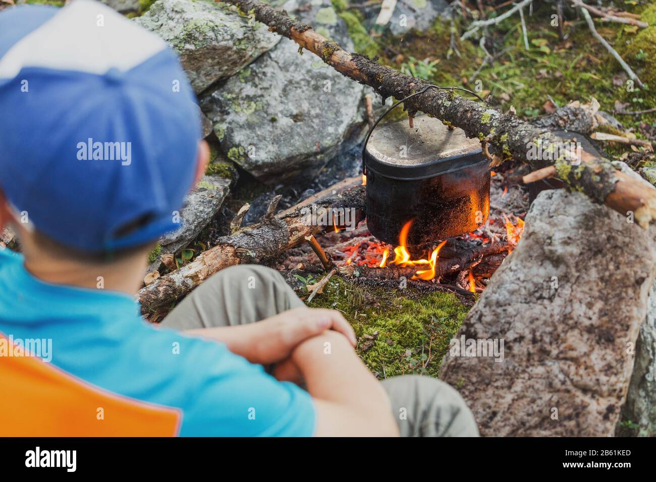 Young boy cooking camp food in cauldron on open fire Stock Photo - Alamy