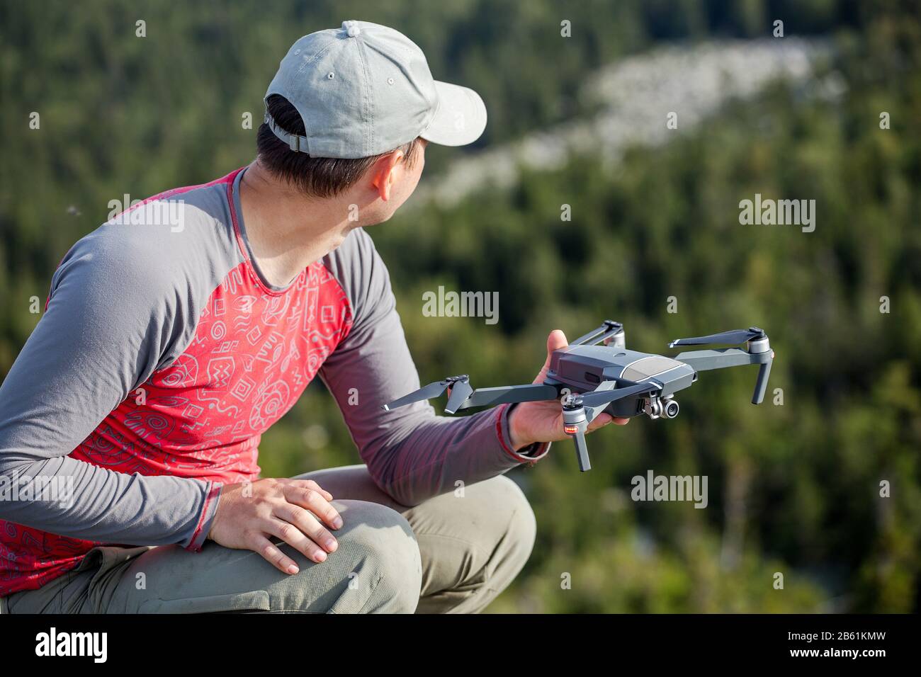 A man launches a modern intelligent quarter copter drone during a hike ...