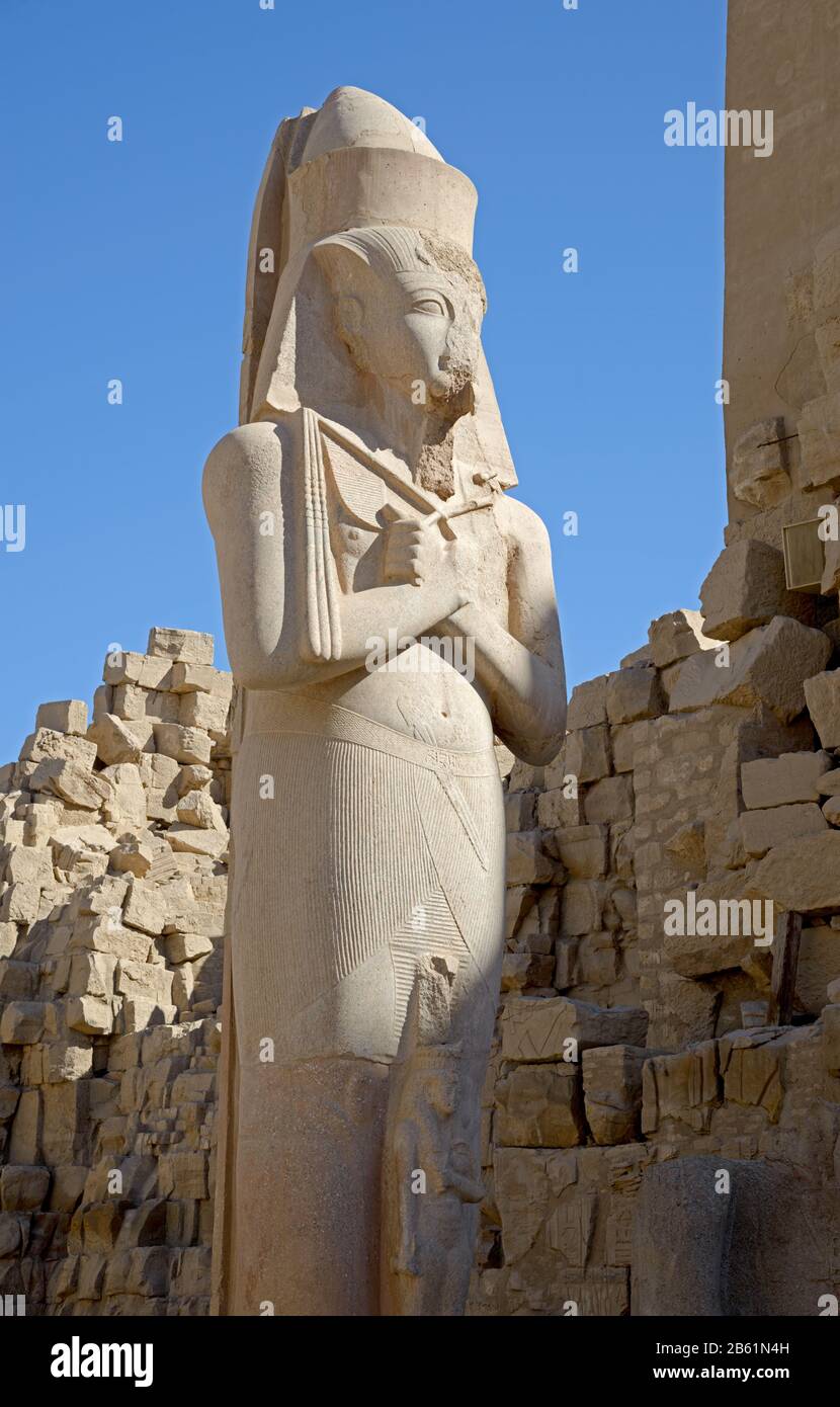 Ramses II statue close-up against old ruins and blue sky background ...