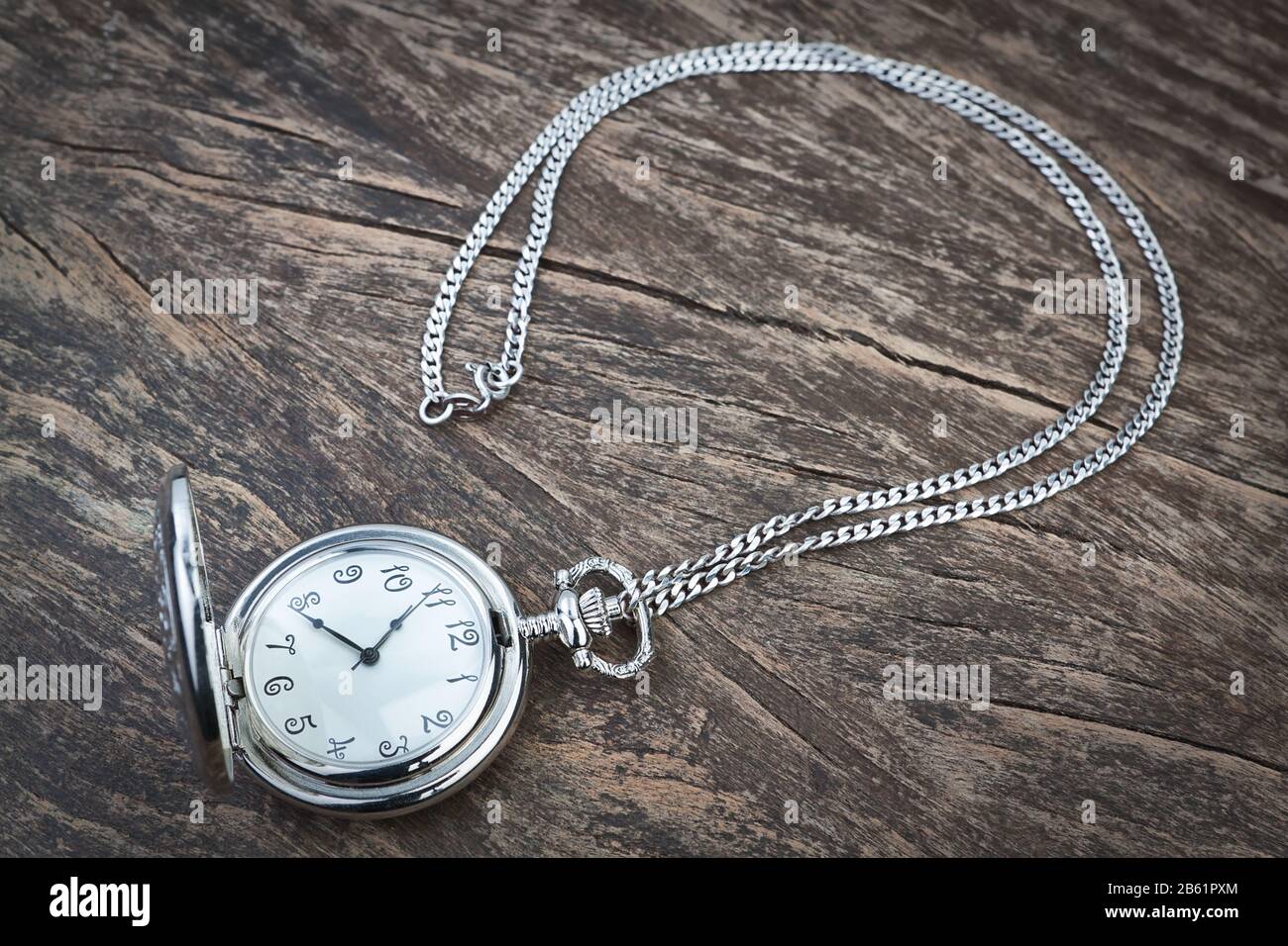 Silver pocket watch on a chain, a wooden texture. Conceptual ...