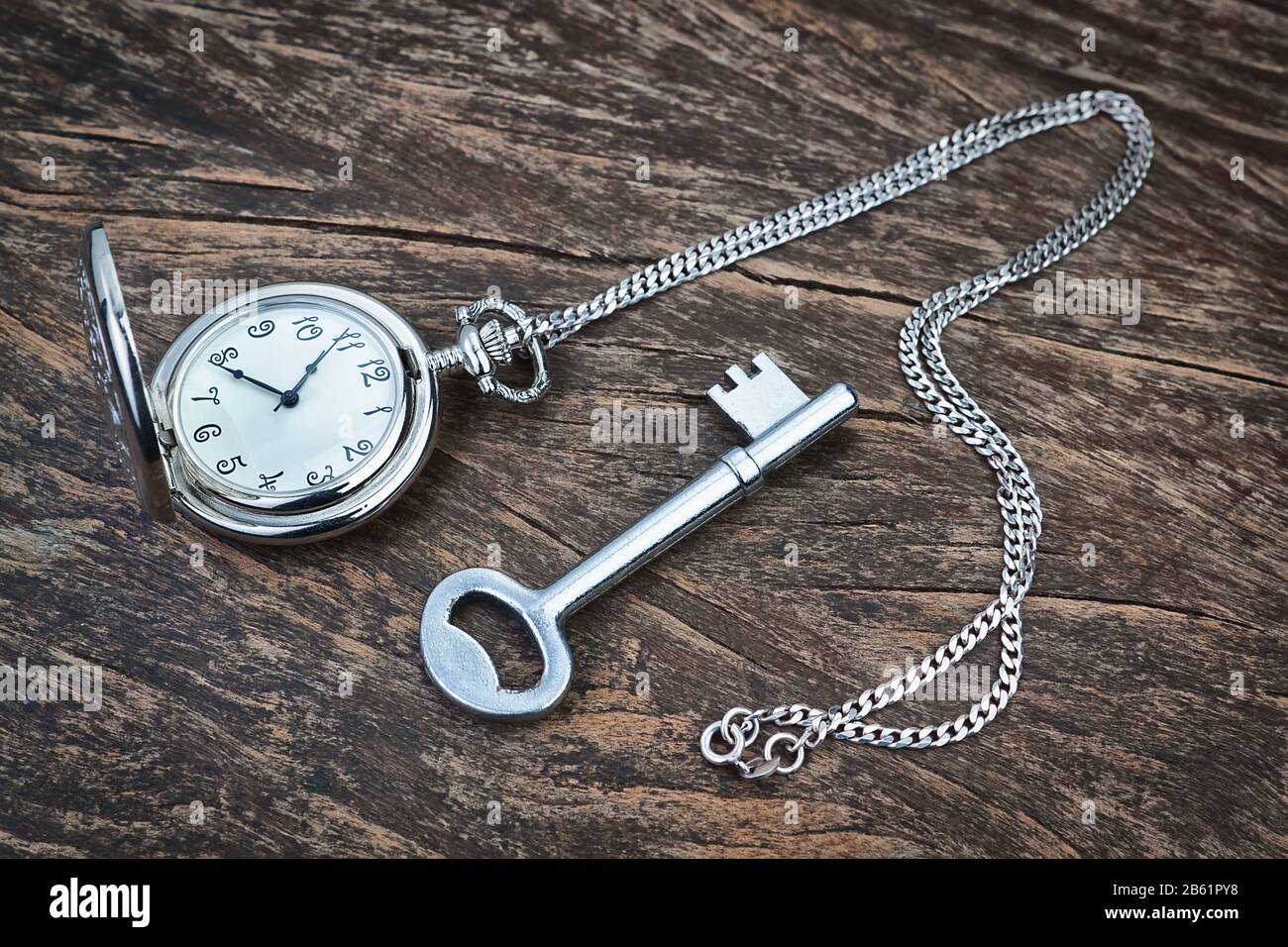 Silver pocket watch and key on wooden texture. Conceptual photography ...
