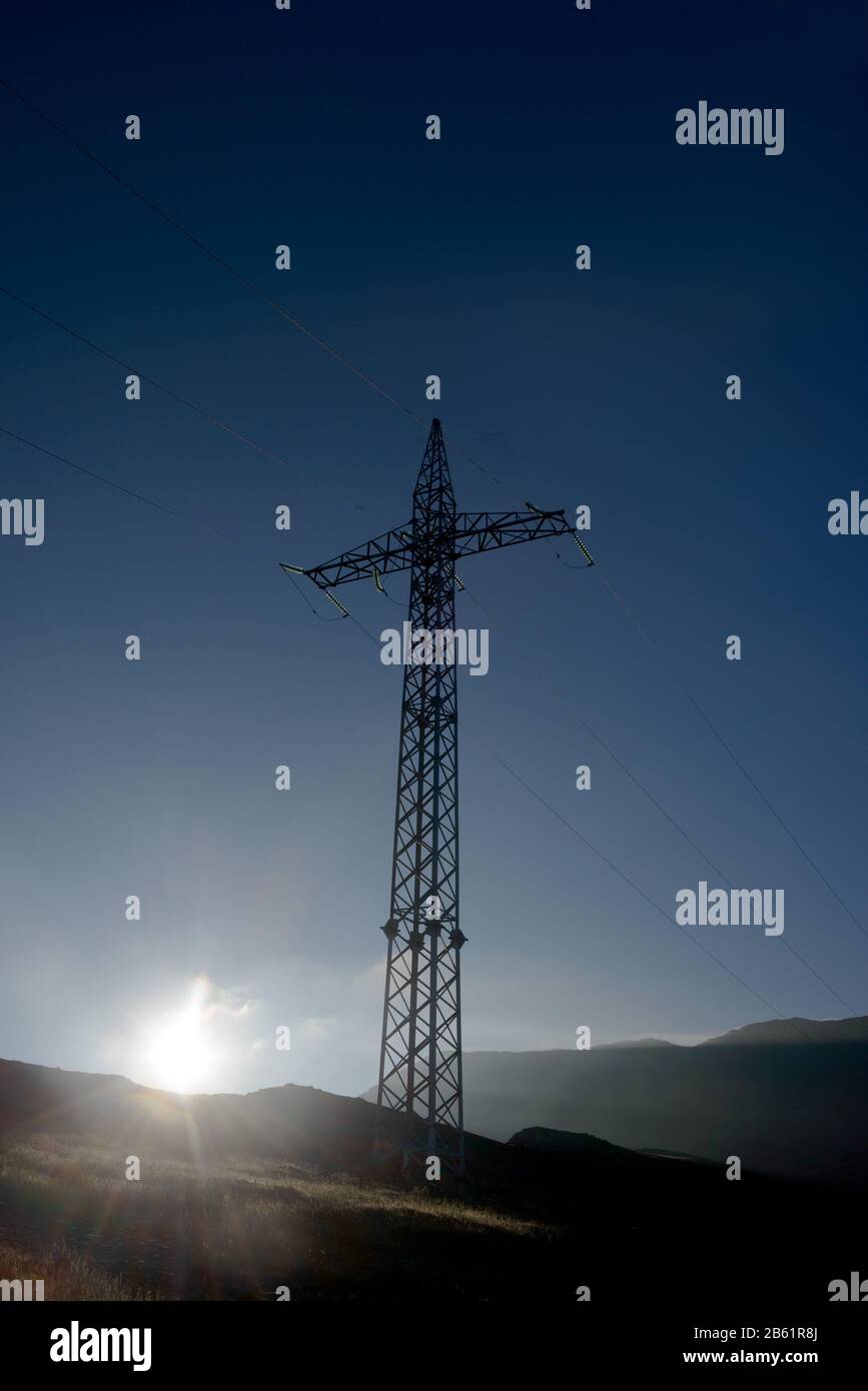 High-voltage power line pylon against blue morning sky background ...