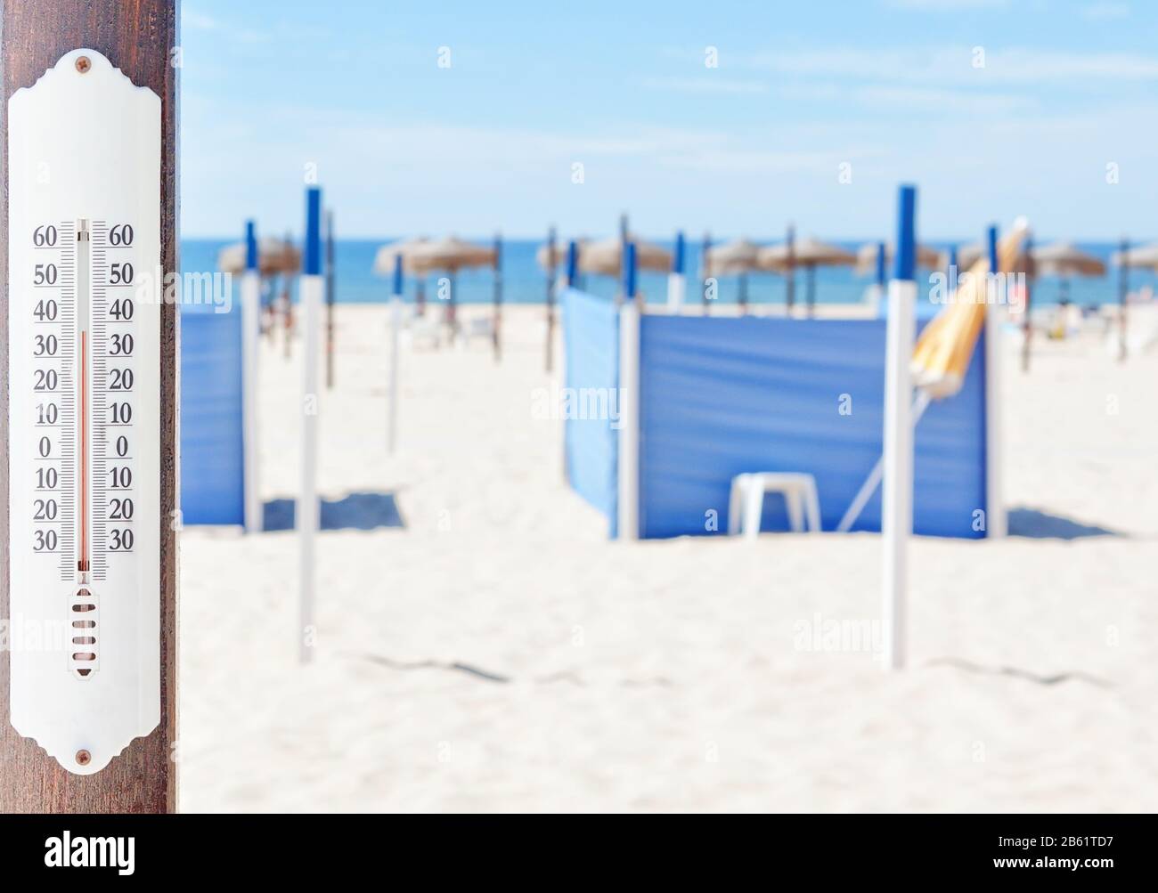 A thermometer on the beach in the summer, in the background of sun beds ...