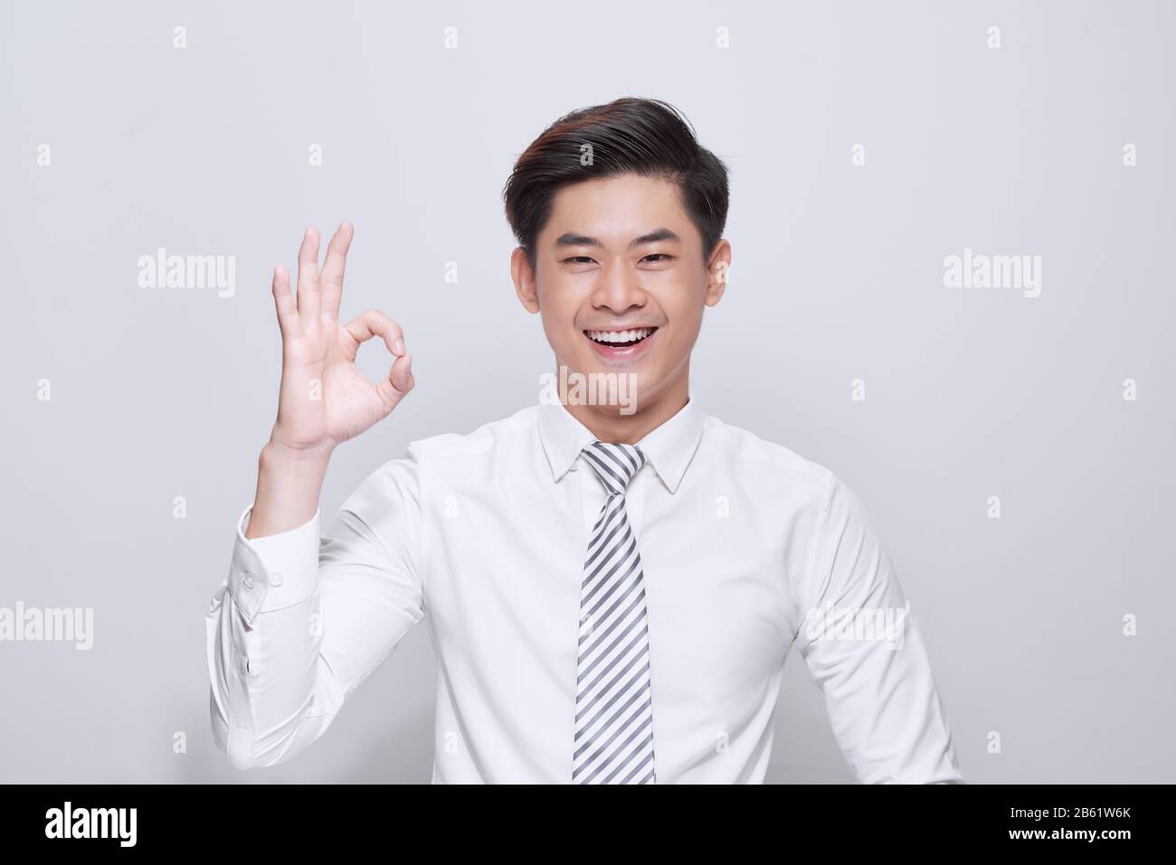 Portrait of a cheerful young man showing okay gesture isolated on the ...