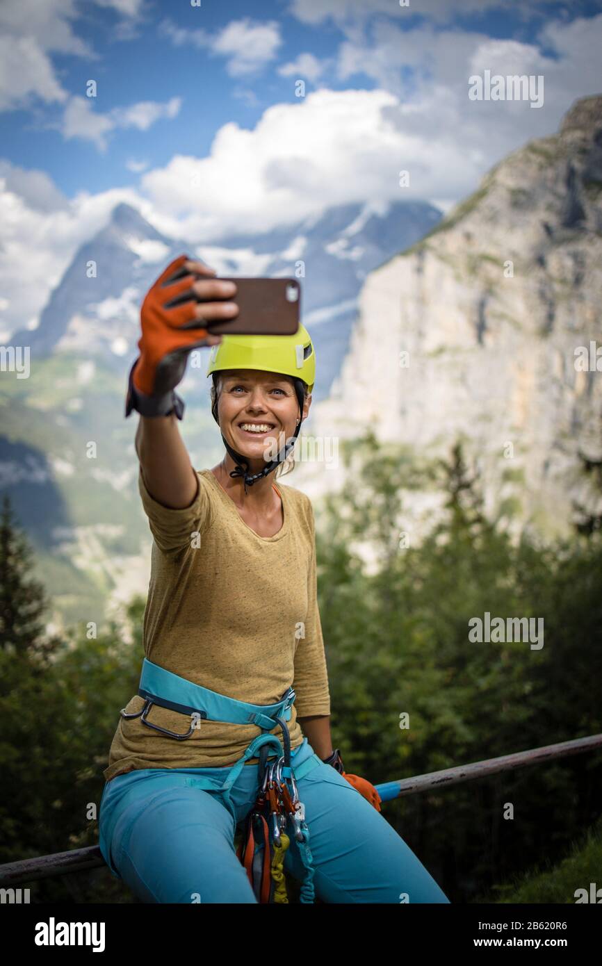 Pretty, female climber on a via ferrata - climbing on a rock in Swiss ...