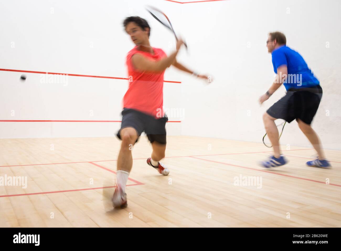 Squash players in action on a squash court (motion blurred image; color ...