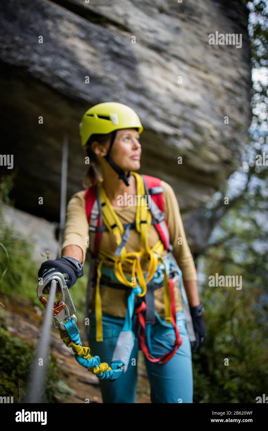 Pretty, female climber on a via ferrata - climbing on a rock in Swiss ...