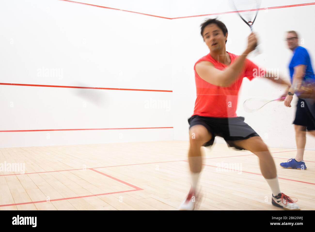 Squash players in action on a squash court (motion blurred image; color ...