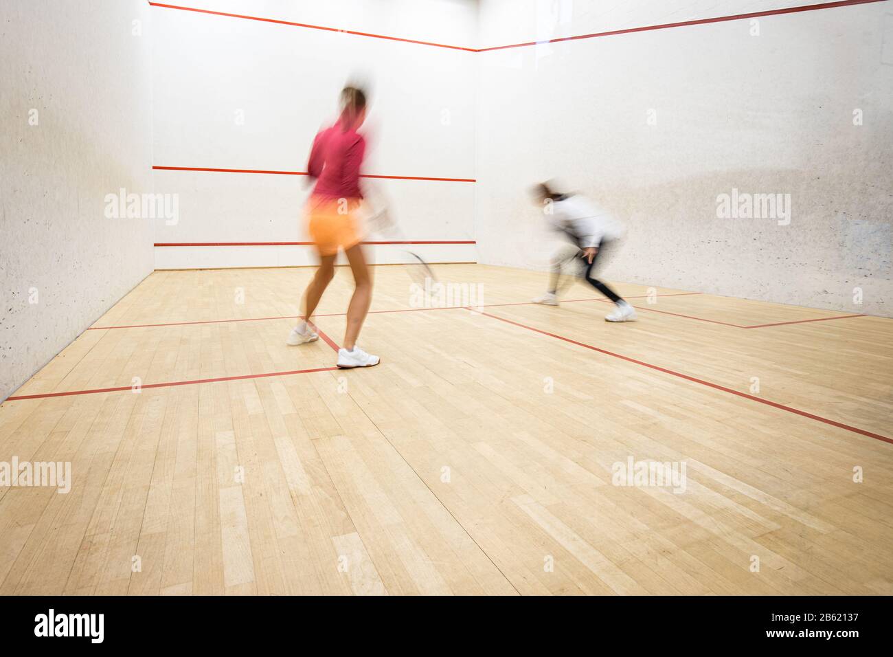 Two female squash players in action on a squash court (motion blurred ...