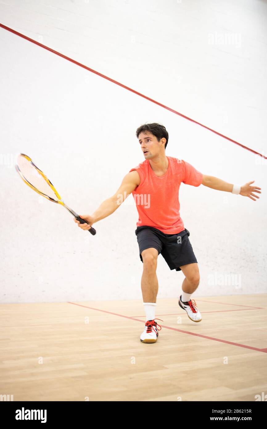 Squash player in action on a squash court (motion blurred image; color ...