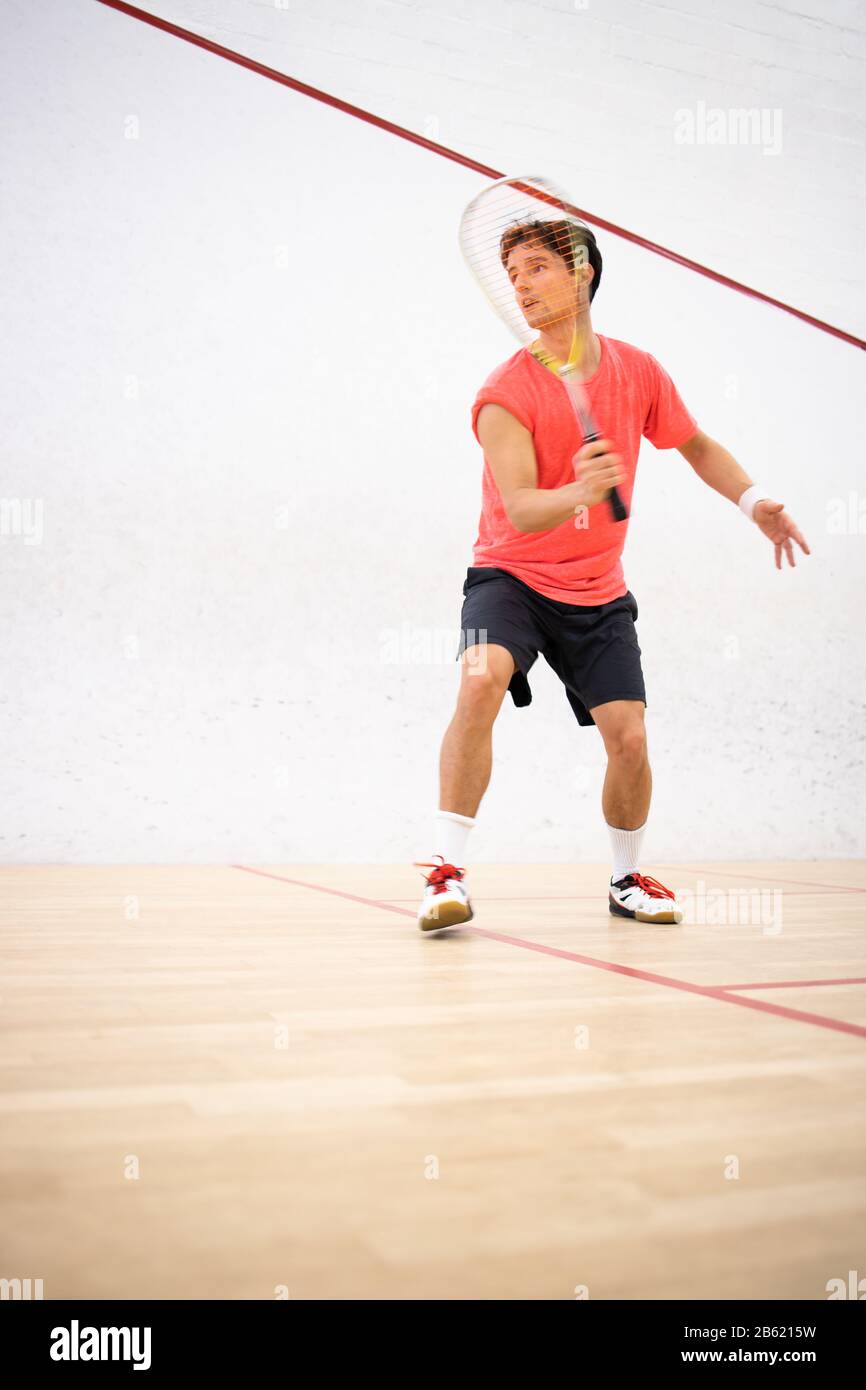Squash player in action on a squash court (motion blurred image; color ...