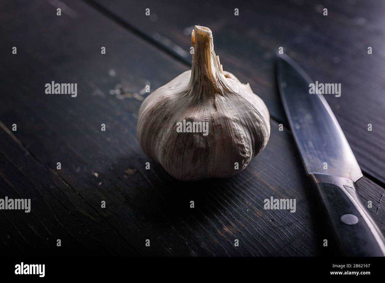 Garlic bulbs and knife on a dark background. Low key lighting Stock ...