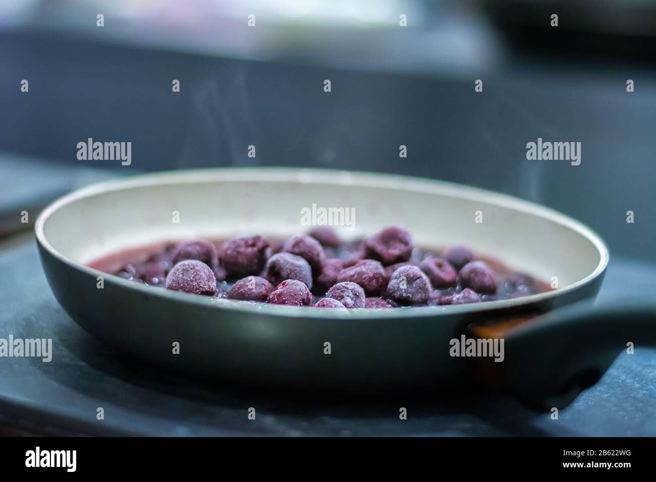 Frozen cherries in the pan. Defrosting Stock Photo - Alamy