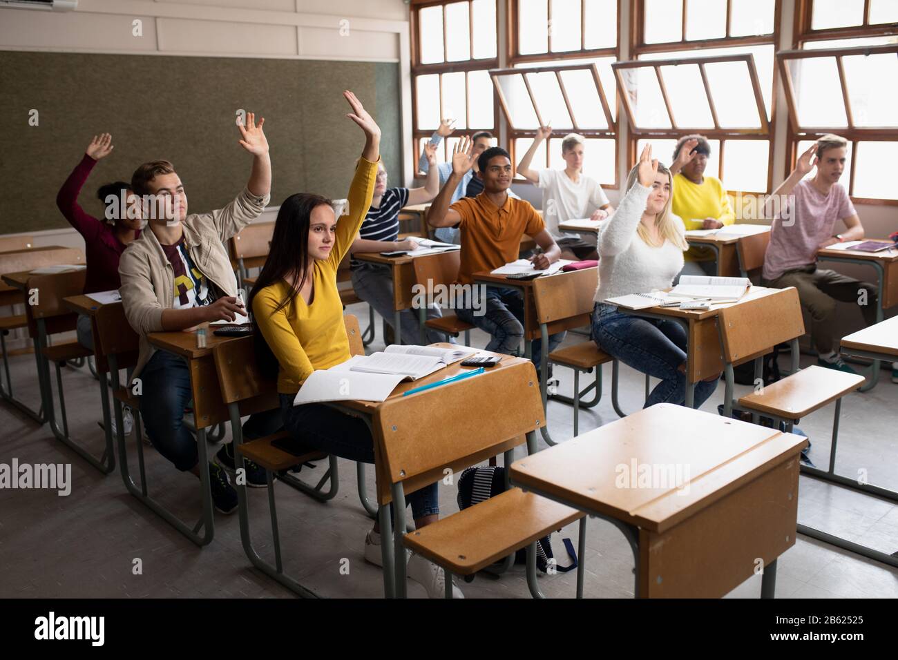 Girl and boy raising hand in classroom hi-res stock photography and ...