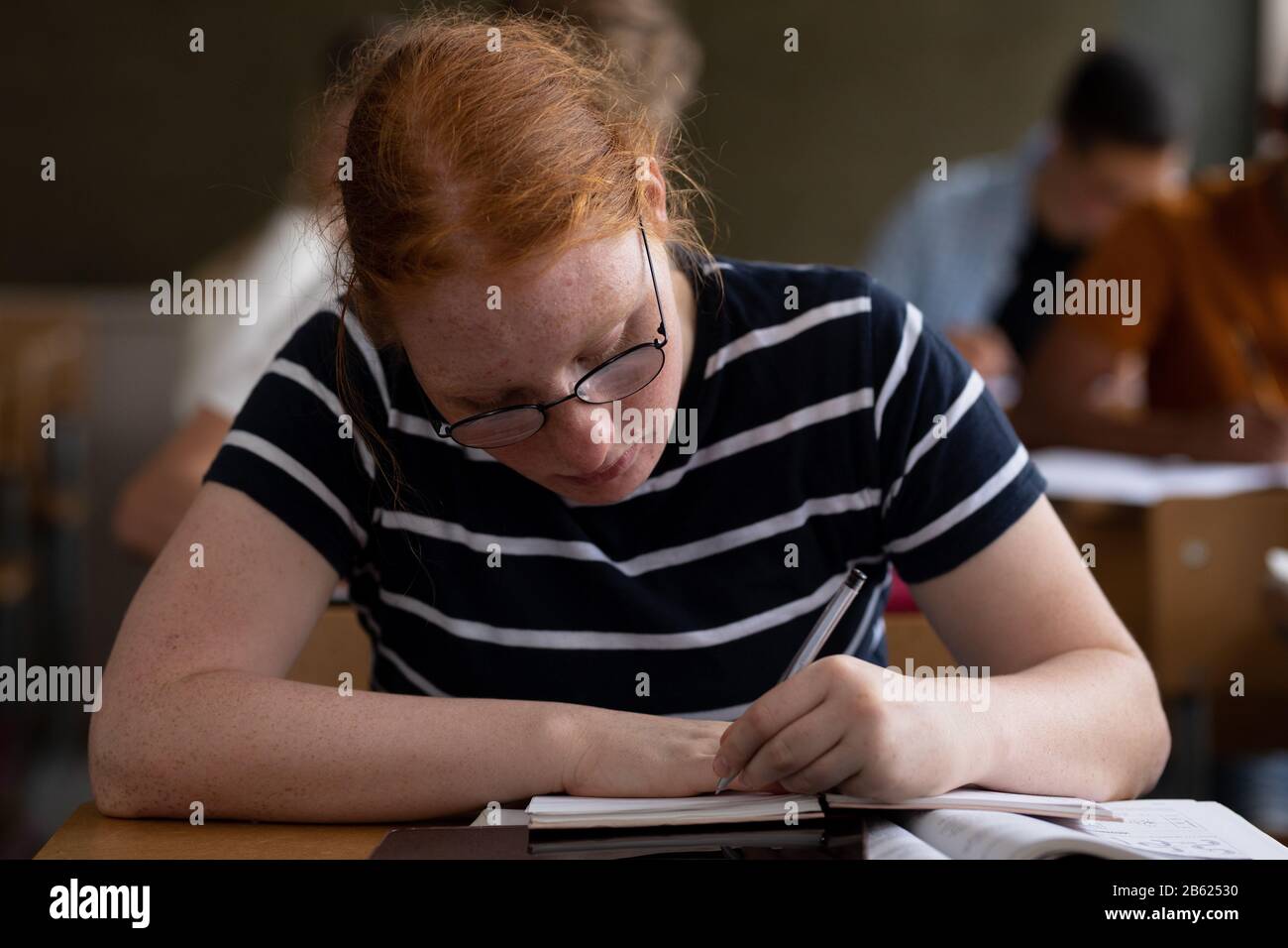 Front view of student writing in class Stock Photo - Alamy