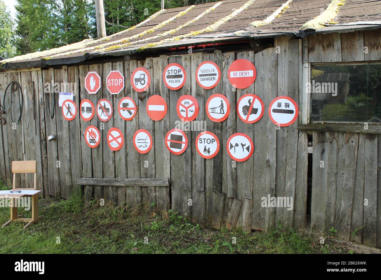 Many road signs hang on the wall of a wooden rural building with a ...