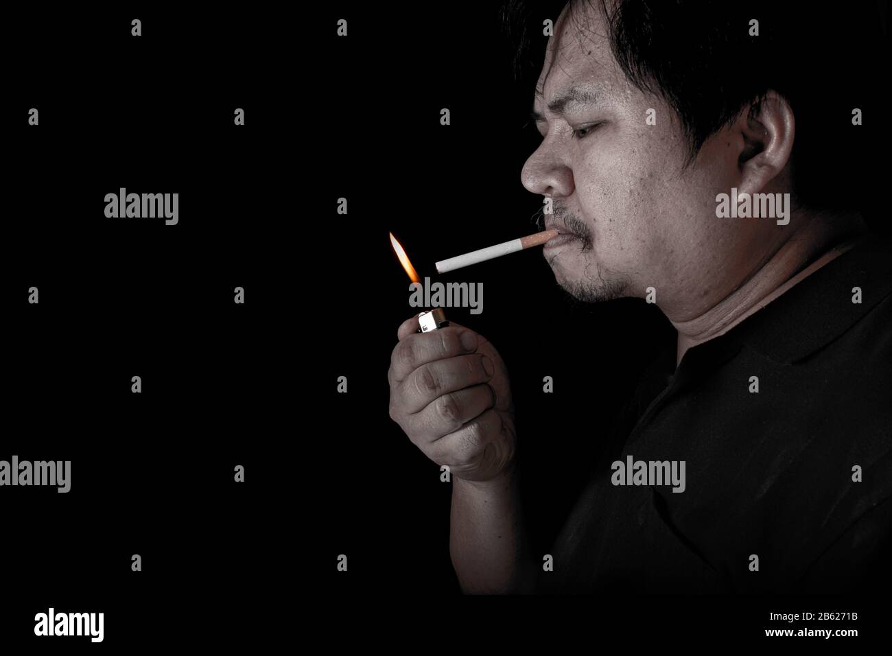 The fat man lighting up a joint with lighter smoking at the black ...