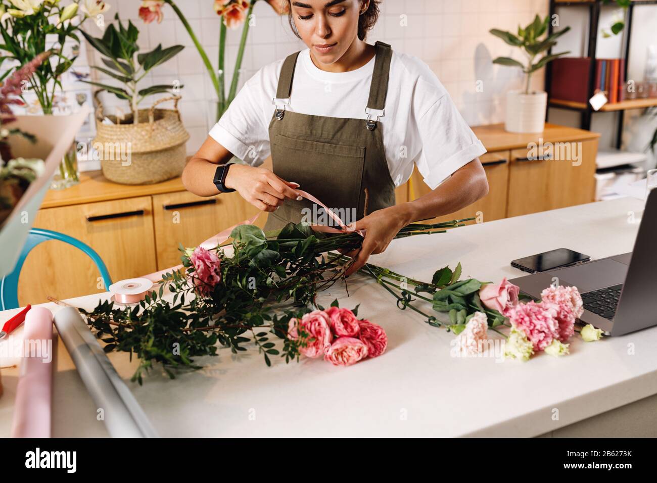 Woman florist making a bouquet at counter in small flower shop Stock ...