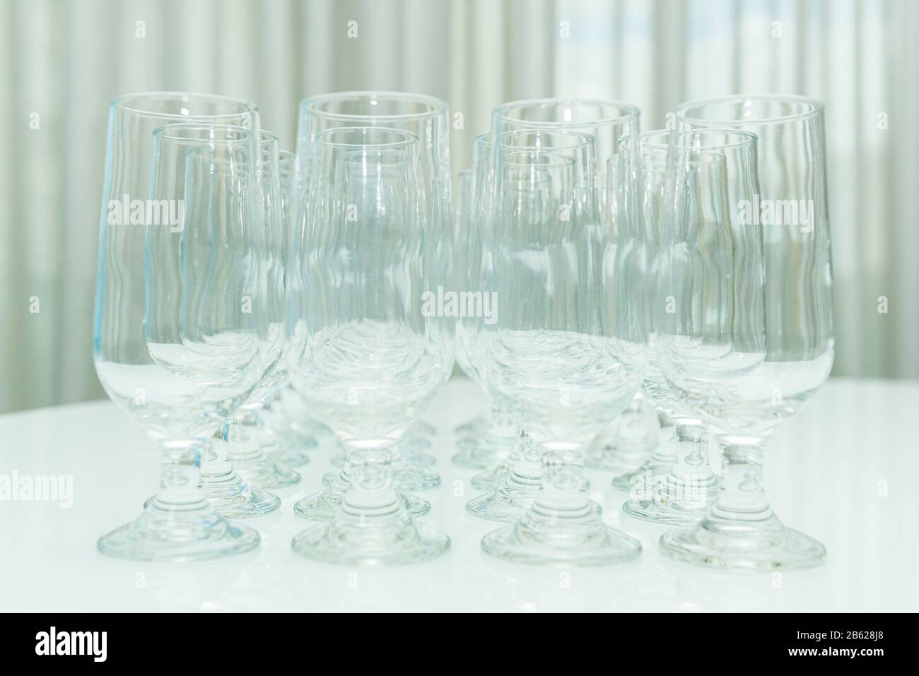 Empty crystal glasses side by side on white table. Collection of ...