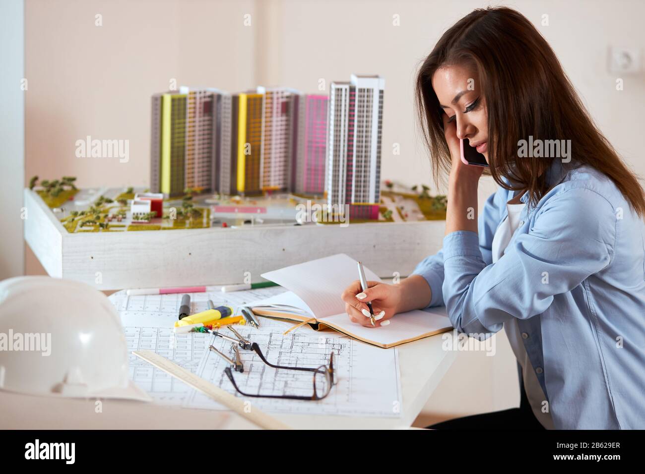 beautiful young awesome female architect drawing model in the paper ...