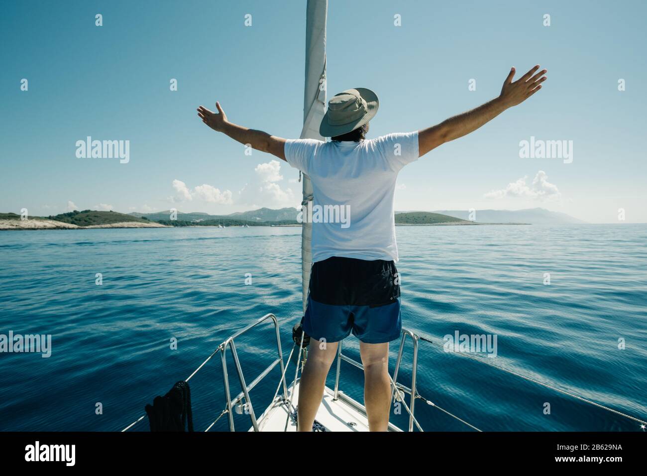 Man standing on the ships bow enjoying the yacht trip with arms wide ...